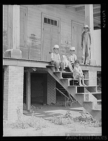 Children of mulatto family sitting on steps of very old...