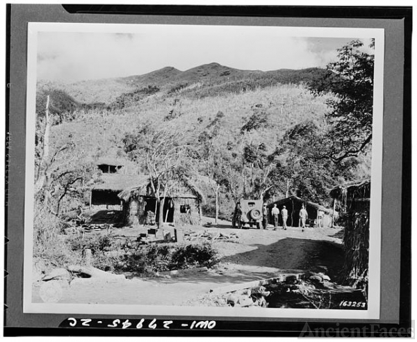 Soldiers live in native-type huts in a small bivouac area...