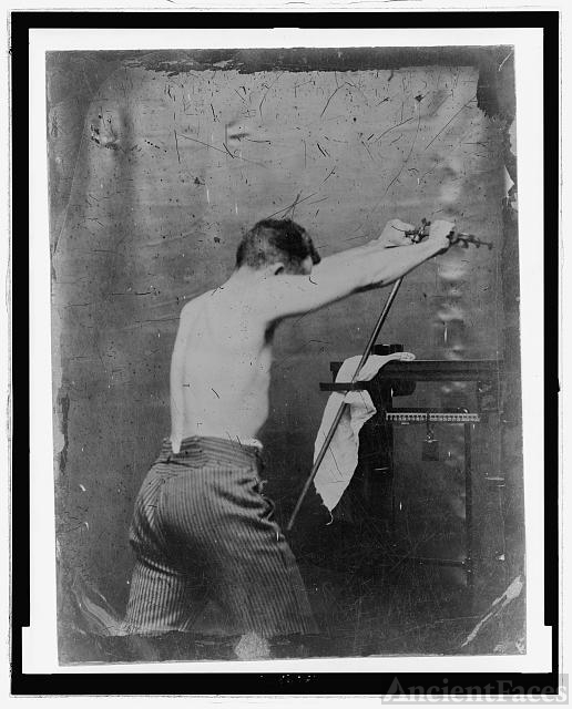 [Side view of a shirtless man pushing a metal bar which...