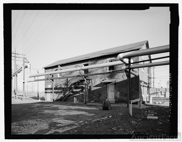 WEST ELEVATION, CAMERA FACING EAST. THE OVERHEAD PIPES...