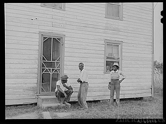 John Barnes with his sons in front of their house. He is...